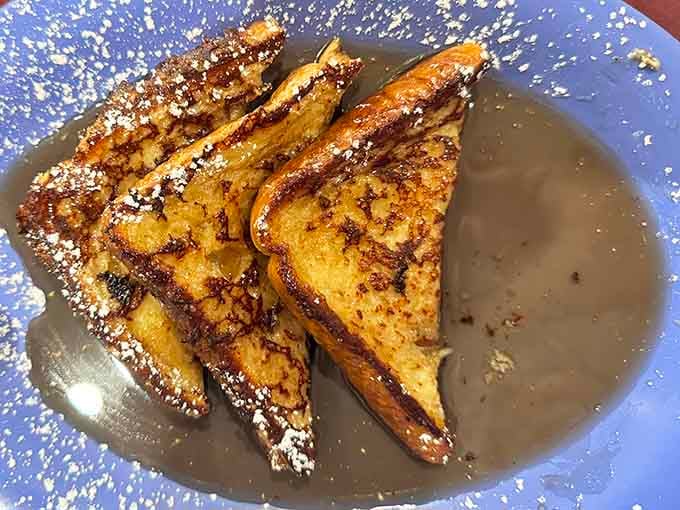 French toast dusted with powdered sugar and swimming in syrup, proving that sometimes breakfast should feel like dessert.