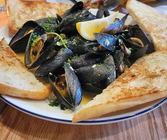 Fresh mussels glistening in garlic broth, served with grilled bread that's basically edible utensils for happiness.