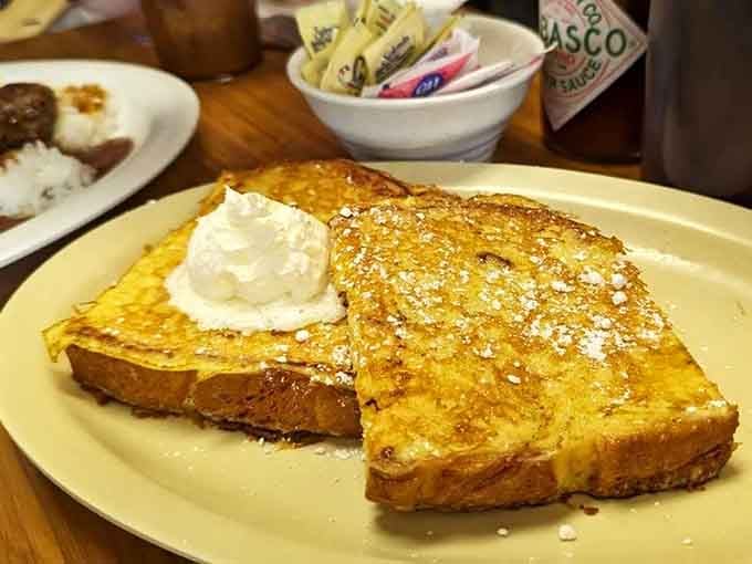 French toast that's had its passport stamped in paradise &ndash; thick-cut, golden-brown, and dusted with powdered sugar like a light Hawaiian snowfall.