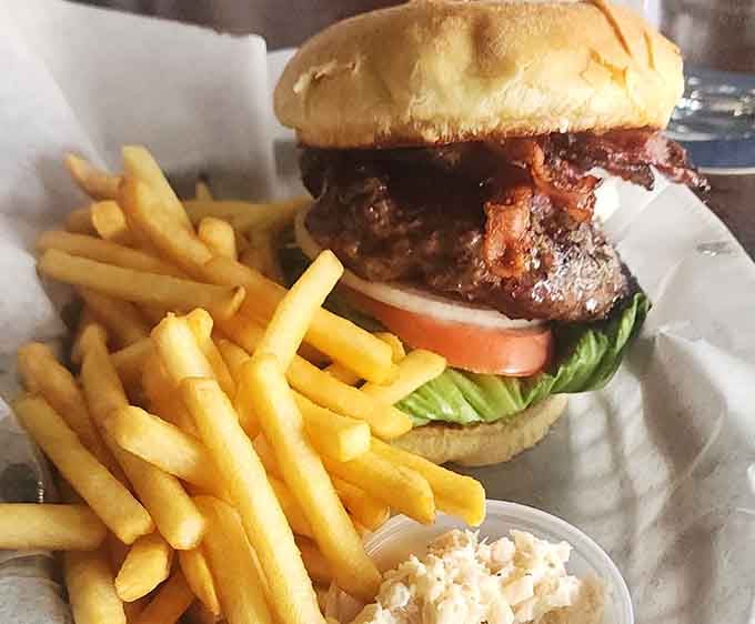 That burger sits tall and proud, surrounded by crispy fries and coleslaw, ready for its close-up.
