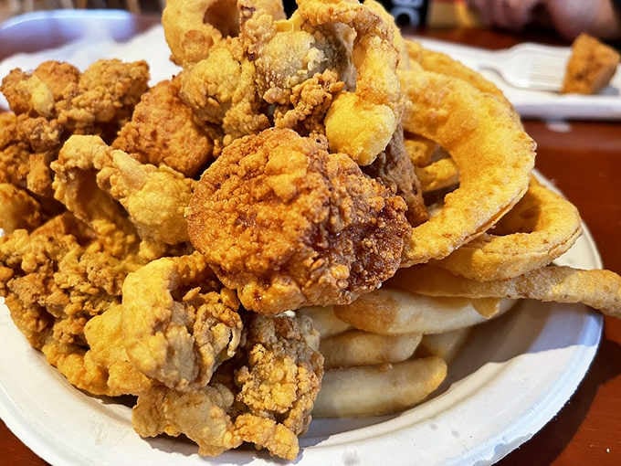 Whole belly clams fried to crispy perfection, stacked like edible treasure on a mountain of hand-cut fries.