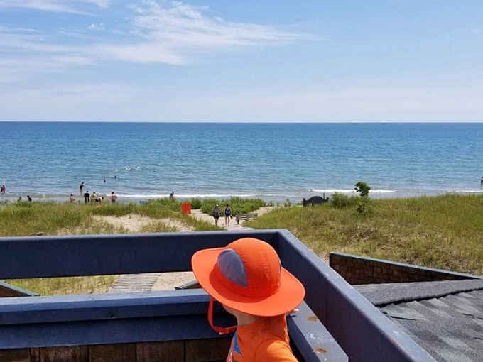 That orange hat knows what's up: prime beach real estate with front-row seats to Lake Michigan's daily show.