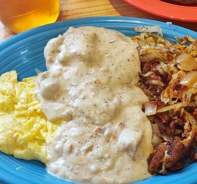 Biscuits drowning in peppery gravy alongside golden hash browns, this is comfort food that actually comforts your soul.