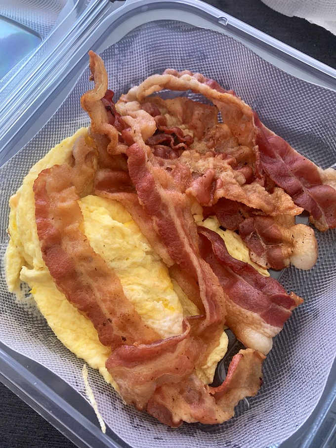 Crispy bacon curled like edible ribbons next to fluffy scrambled eggs, the breakfast duo that never disappoints.