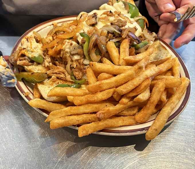 Spicy chicken cheesesteak piled high with peppers, onions, and enough fries to share, maybe.