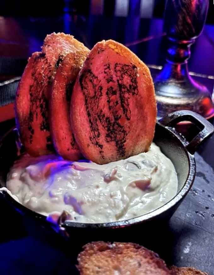 Toast points standing at attention like they're guarding the most decadent artichoke dip you'll ever encounter.