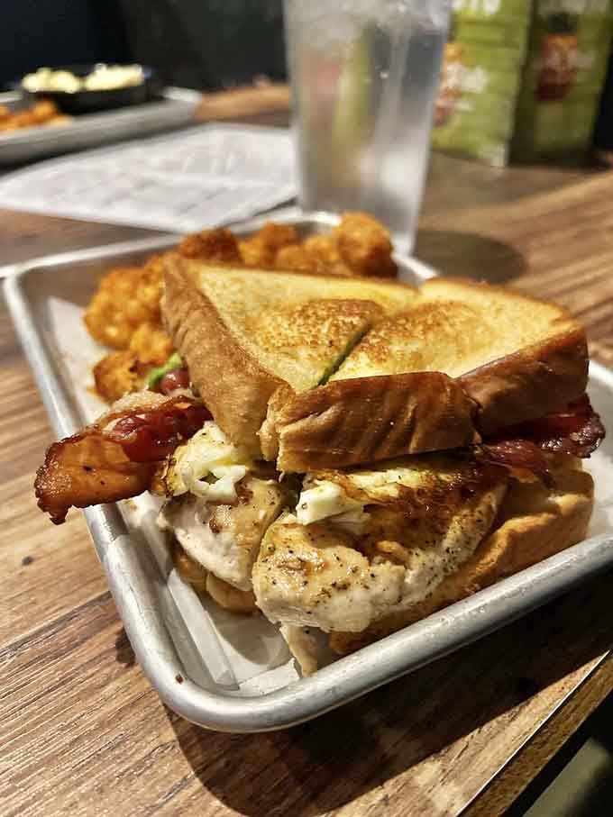 Bacon peeking out from toasted bread like it's trying to escape before you devour this masterpiece.