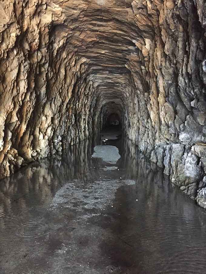 Water pools on the floor create mirror images, doubling the drama of this hand-carved underground passage.