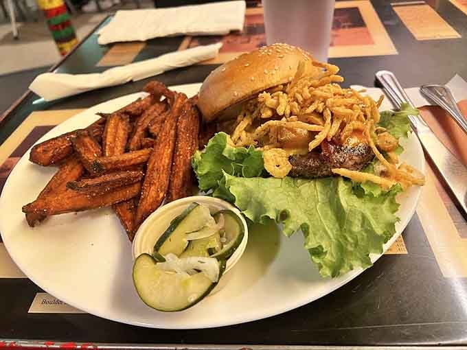 The BBQ bacon burger arrives with crispy sweet potato fries and house-made pickles for the complete experience.
