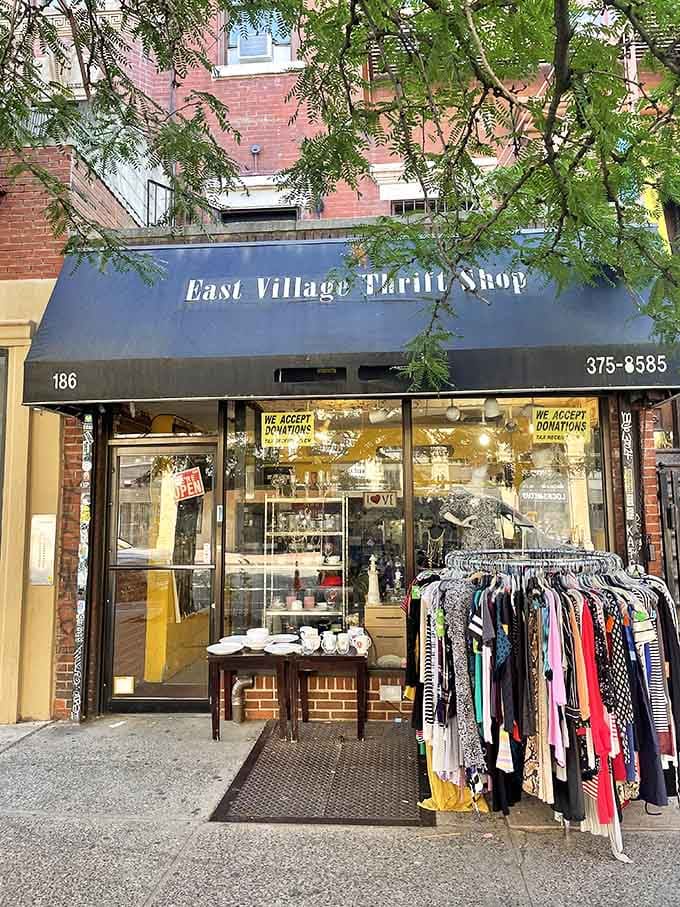 Tree branches frame this charming thrift shop entrance, where outdoor clothing racks invite sidewalk browsing before you even step inside.