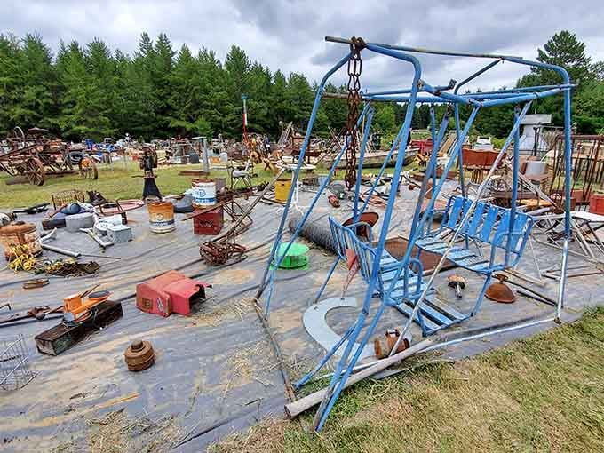 That vintage blue swing set stands like a monument to childhood memories, surrounded by rusty relics and forgotten farm tools.