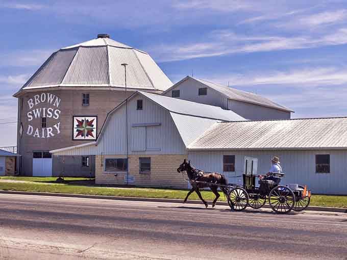 A horse-drawn buggy passes the iconic dairy barn where tradition isn't performance art but simply daily life.