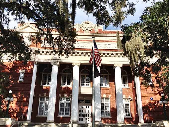 Red brick and white columns stand dignified under oak shade, flying the flag with unmistakable Southern pride.