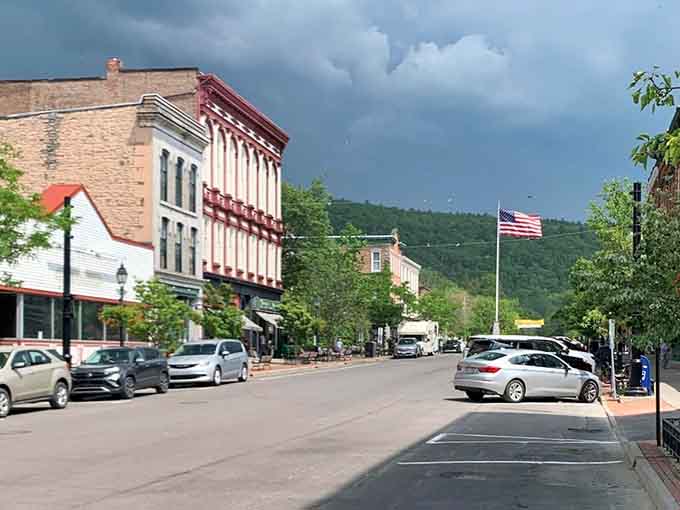 Storm clouds gather dramatically over brick facades while the American flag stands tall against nature's theatrical backdrop.