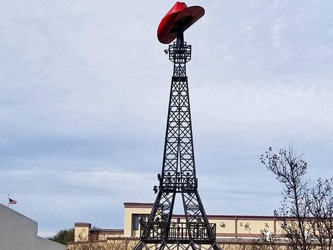 The crimson tower rises against blue skies, flanked by American flags that celebrate this uniquely Texan interpretation of France.