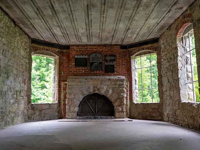 The fireplace and arched windows suggest this castle room once hosted gatherings far more elegant than today's emptiness.