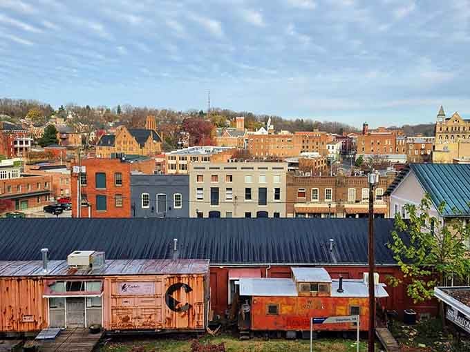 Old train cars sit peacefully among brick buildings, turning industrial history into charming neighborhood character that money can't buy.