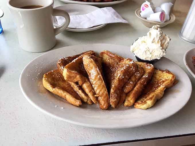 French toast that understands its assignment, arriving golden and dusted with powdered sugar like edible snow on delicious mountains.