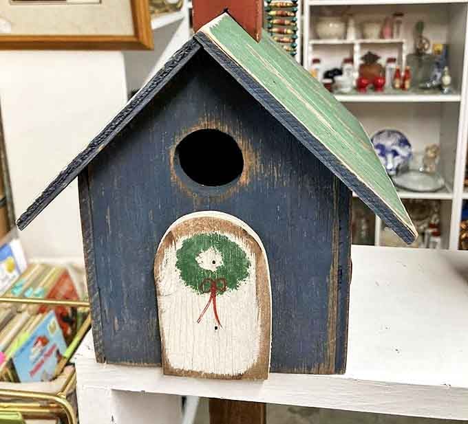 Not just a birdhouse, but a tiny blue cottage where feathered residents probably pay rent in songs and occasional window performances.