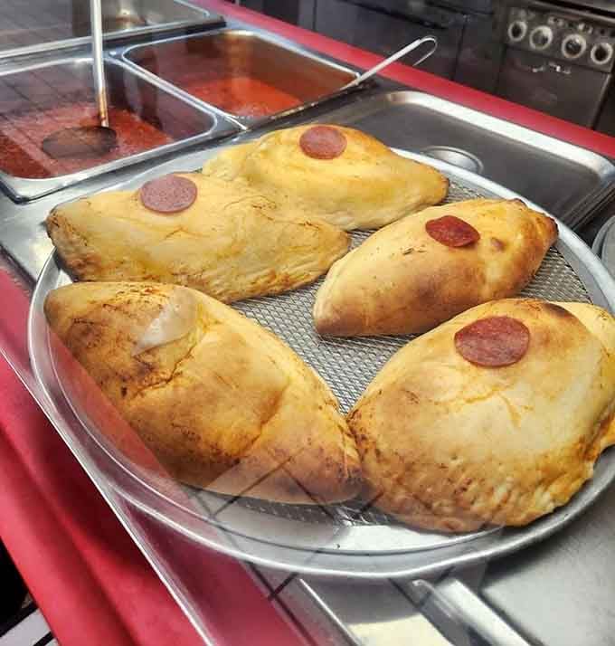 Golden-brown calzones marked with pepperoni medallions wait their turn, promising pockets of molten cheese and savory fillings that'll make your taste buds dance.