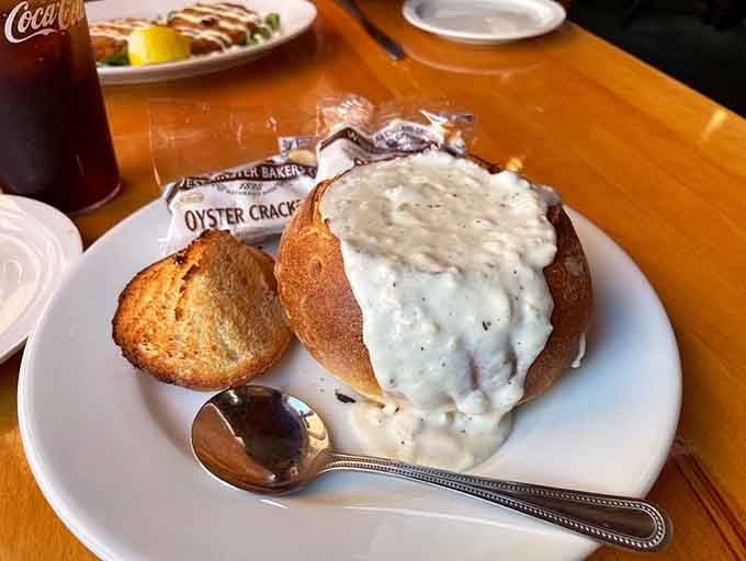 A bread bowl overflowing with legendary clam chowder, proving that edible dishes are humanity's greatest invention.