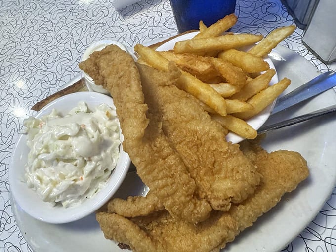 Golden-fried catfish that crunches like autumn leaves, served with fries that could make a Frenchman weep and coleslaw creamy enough to make you forget your manners.