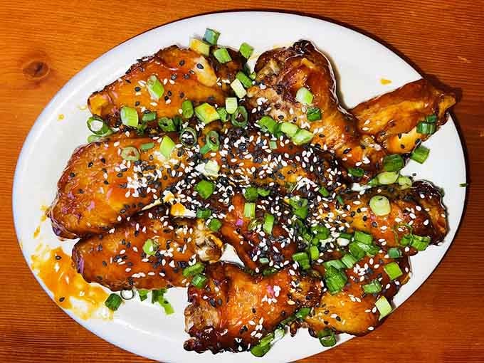 These aren't just wings; they're a sticky, sweet-spicy testament to why napkins were invented. The green onion garnish pretends it's there for health reasons.
