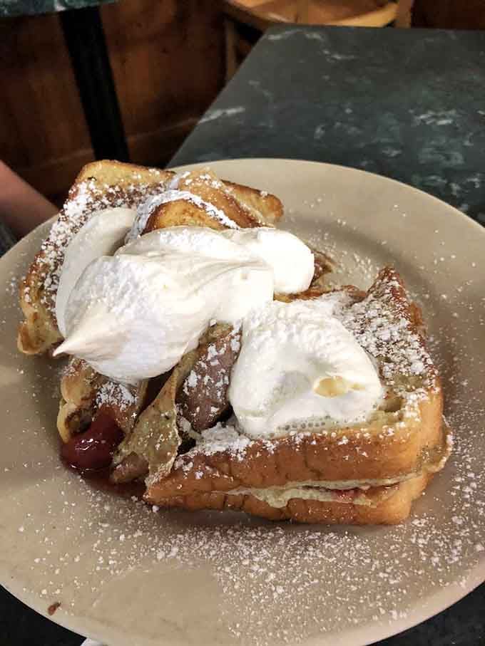 French toast dusted with powdered sugar and topped with whipped cream, because sometimes breakfast should feel like dessert.