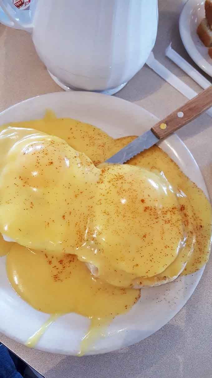 Eggs Benedict drowning in hollandaise sauce, proving that some mornings call for the full royal treatment at the table.