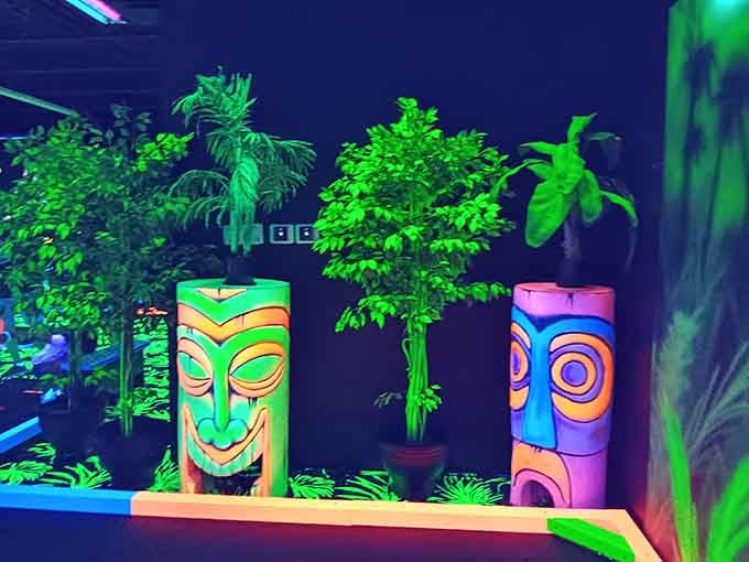 Tiki statues grin mischievously under the blacklight, their carved faces taking on an almost supernatural quality in the glow.