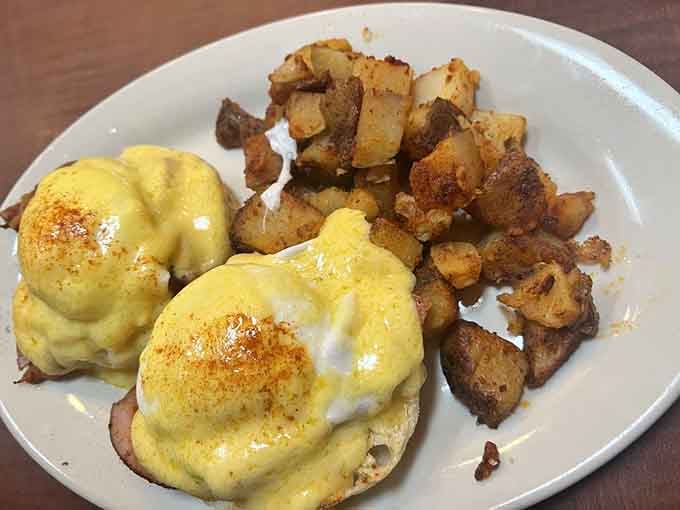 Eggs benedict topped with hollandaise that cascades like a delicious yellow waterfall over perfectly poached eggs.