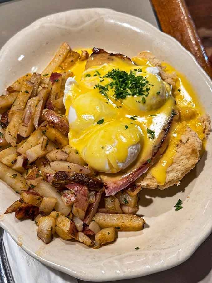 Eggs Benedict done right, with hollandaise cascading like liquid gold over perfectly poached eggs and crispy hash browns.