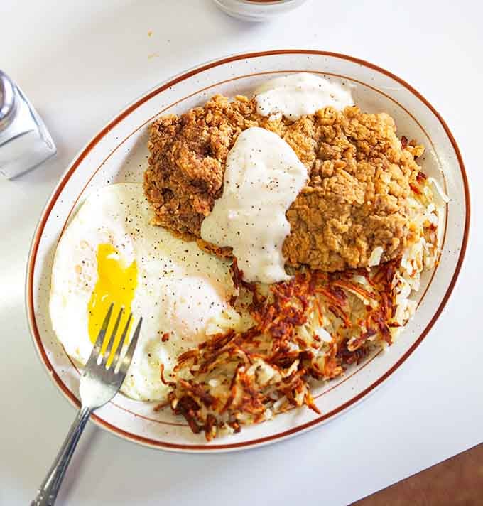 Country gravy cascading over crispy chicken fried steak with hash browns that could win awards at the county fair.