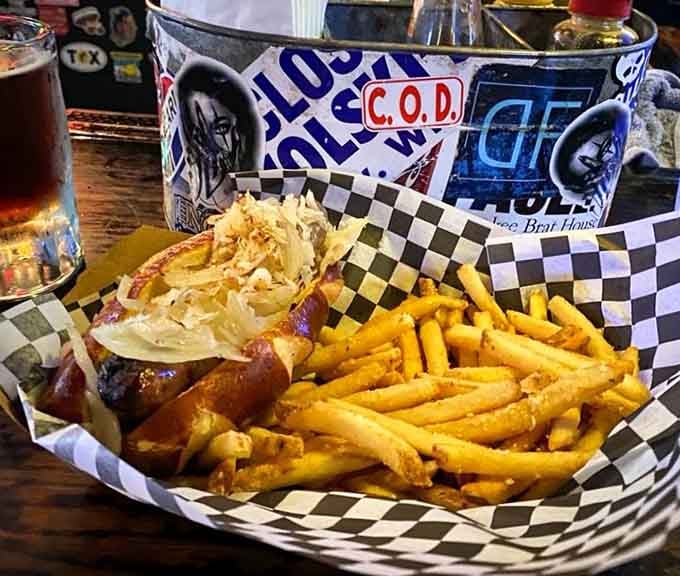 The bratwurst arrives topped with sauerkraut and nestled beside fries, looking exactly like comfort should look on a plate.