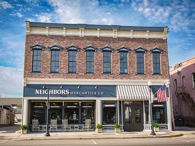 The Neighbors Mercantile storefront showcases classic American architecture with its striped awning and rocking chairs ready for front-porch philosophizing sessions.