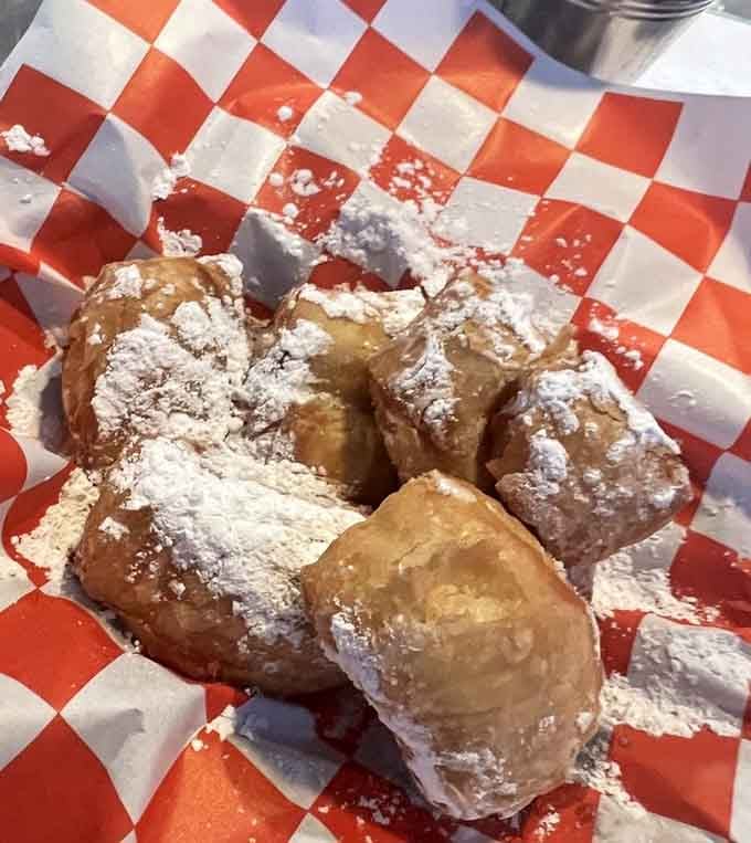Powdered sugar-dusted beignets on red checkered paper are basically edible pillows of joy straight from the French Quarter.
