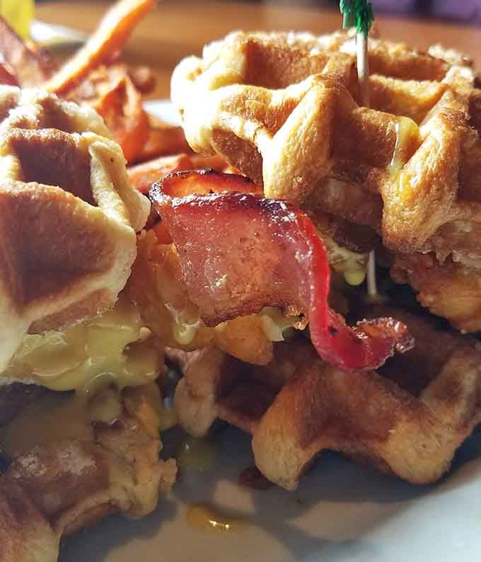 Chicken and waffles meet bacon in a sandwich that defies gravity and possibly several laws of nature in the best way.