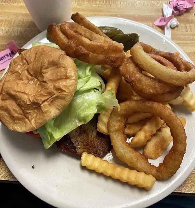 The grilled tilapia sandwich arrives with enough onion rings to make you reconsider your entire lunch strategy.