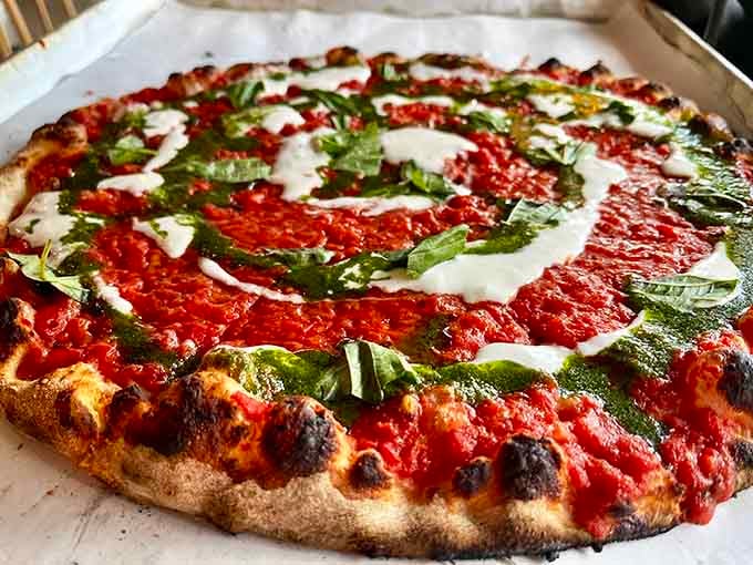 Fresh basil and mozzarella arranged like edible art on a canvas of coal-fired crust and vibrant sauce.