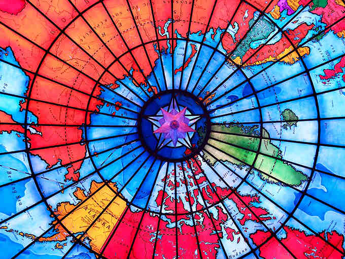 From below, the compass rose radiates outward like a starburst, anchoring this colorful world in brilliant geometric precision.