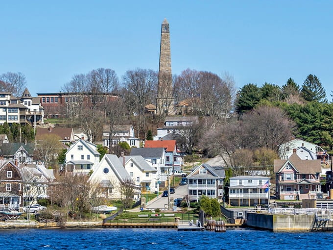 The old stone monument rises above waterfront homes, marking history while neighbors go about their daily lives.