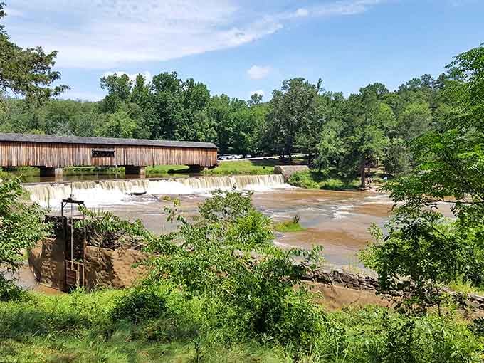 The covered bridge spans rushing water below, connecting past and present with weathered wooden beams.