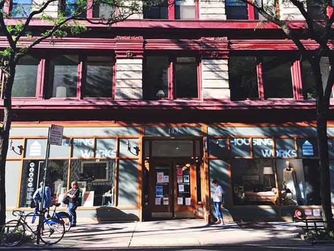 The striking burgundy trim and tree-lined street create an inviting atmosphere for New York's bargain hunters seeking quality finds.
