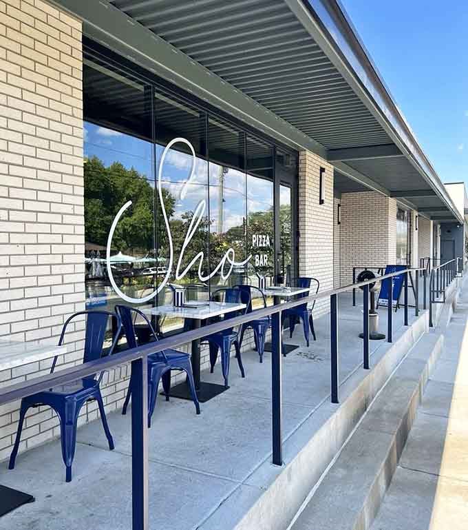 Sho's sleek white brick exterior and blue chairs hint at the modern pizza masterpieces waiting inside.