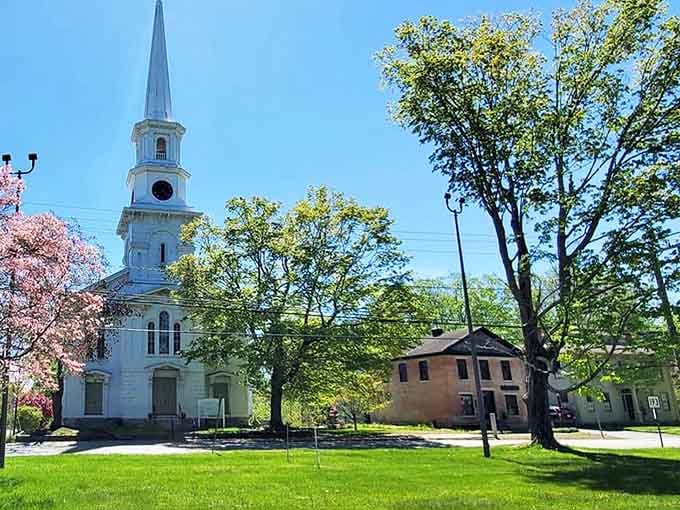 That white steeple pierces spring skies like a beacon, framed by pink blossoms that return faithfully every April.