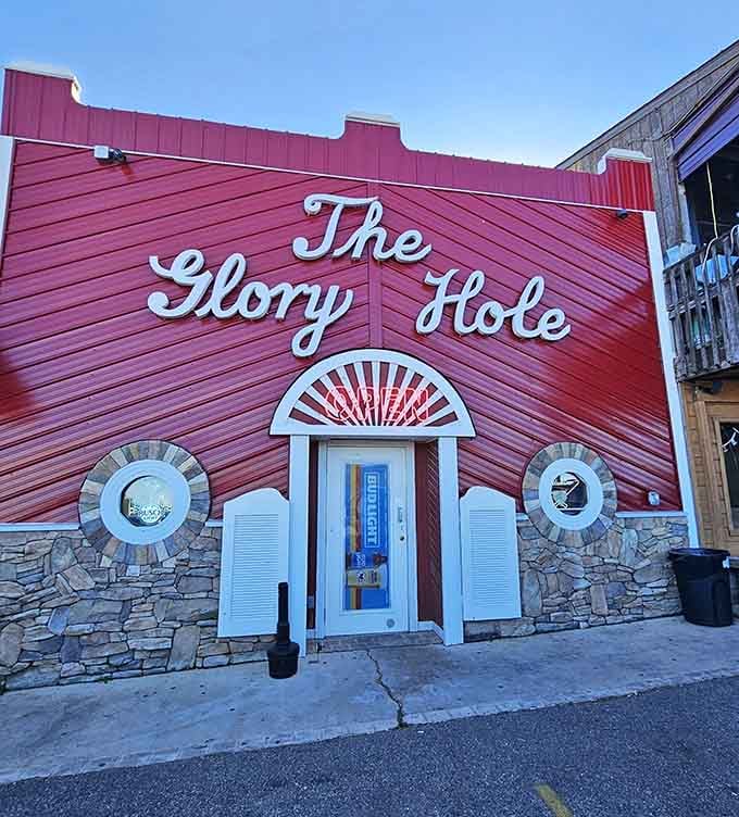 The vibrant coral-red exterior with white script lettering makes this lakeside bar impossible to miss, even if the name makes you chuckle.