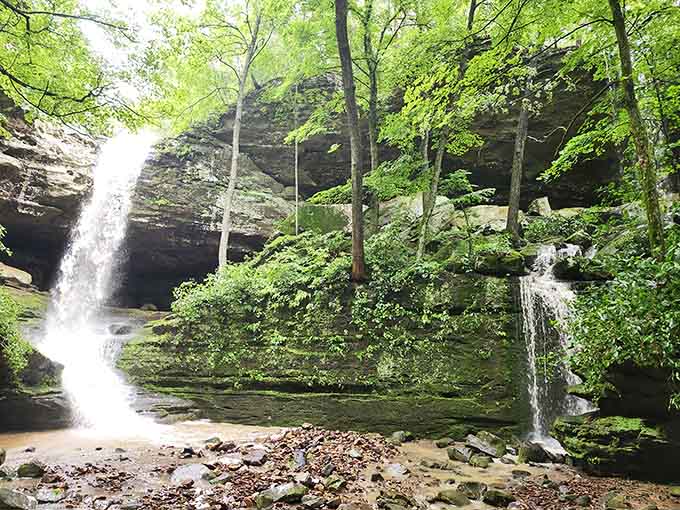 Twin waterfalls frame the main cascade in this moss-covered amphitheater where water writes poetry on ancient stone.