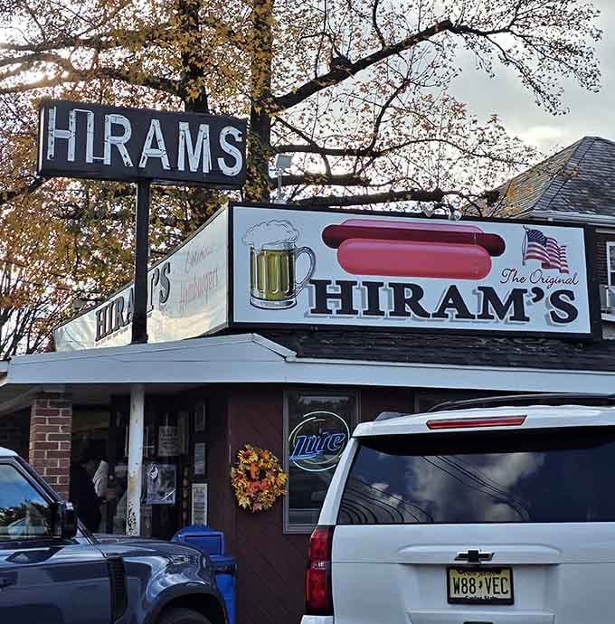 The weathered "HIRAMS" sign stands tall against autumn trees, a monument to the simple perfection of deep-fried hot dogs.