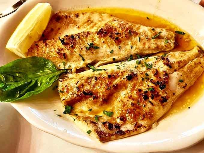 The Branzino Al Forno arrives like Mediterranean sunshine on a plate, delicate fish prepared with the confidence that comes from a century of practice.