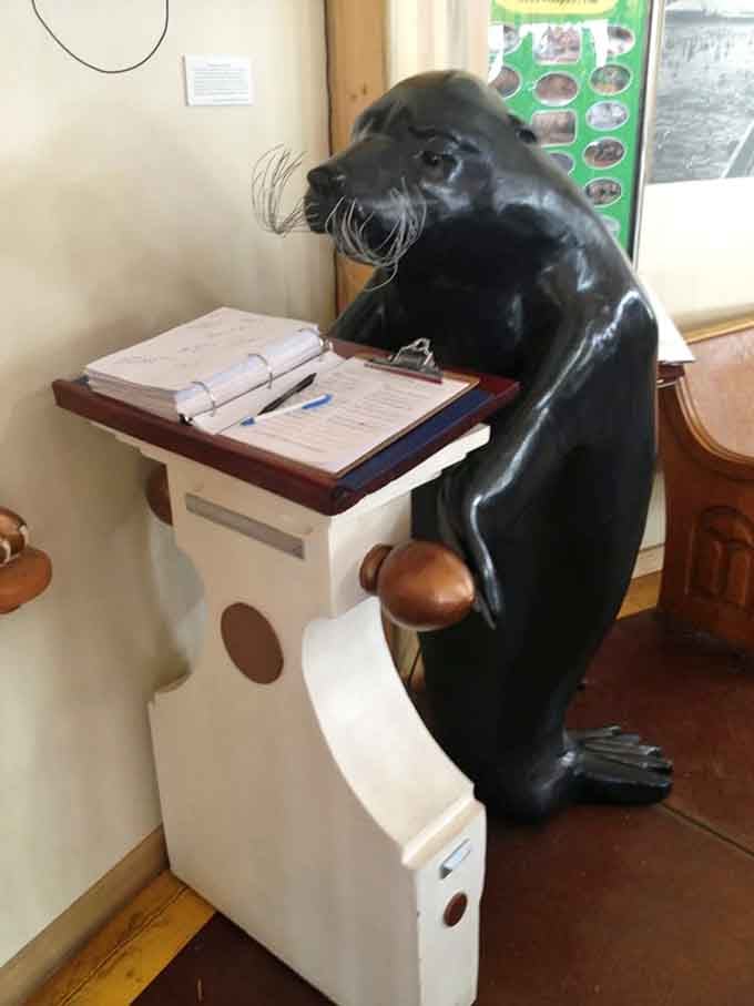 This distinguished gentleman in carved wood form handles guest registration duties with impressive whiskers and unwavering dedication daily.